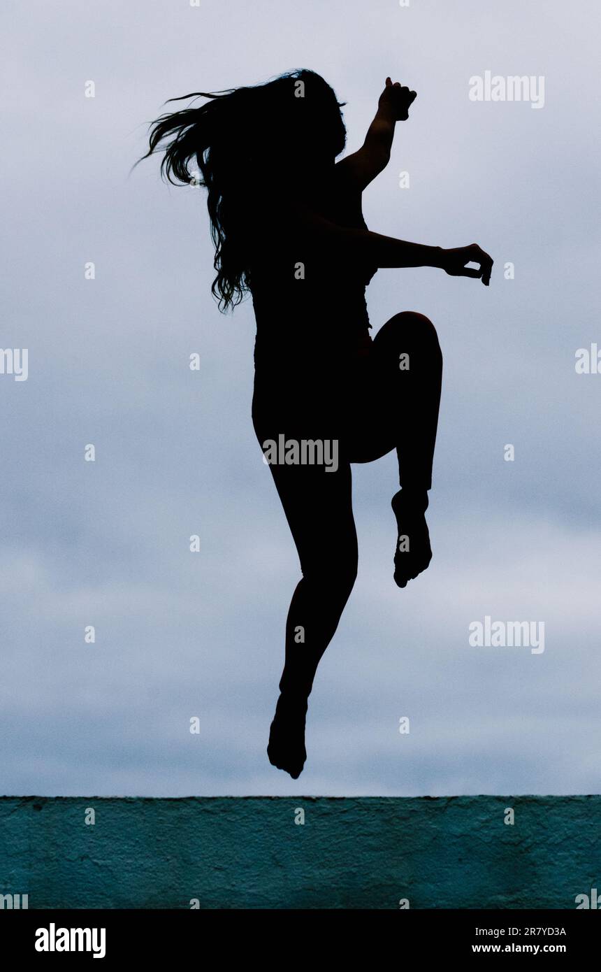 A silhouette of a young female captured mid-air in an artful pose with ...
