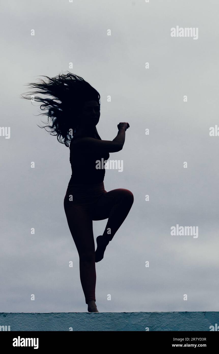 A silhouette of a young female captured mid-air in an artful pose with ...