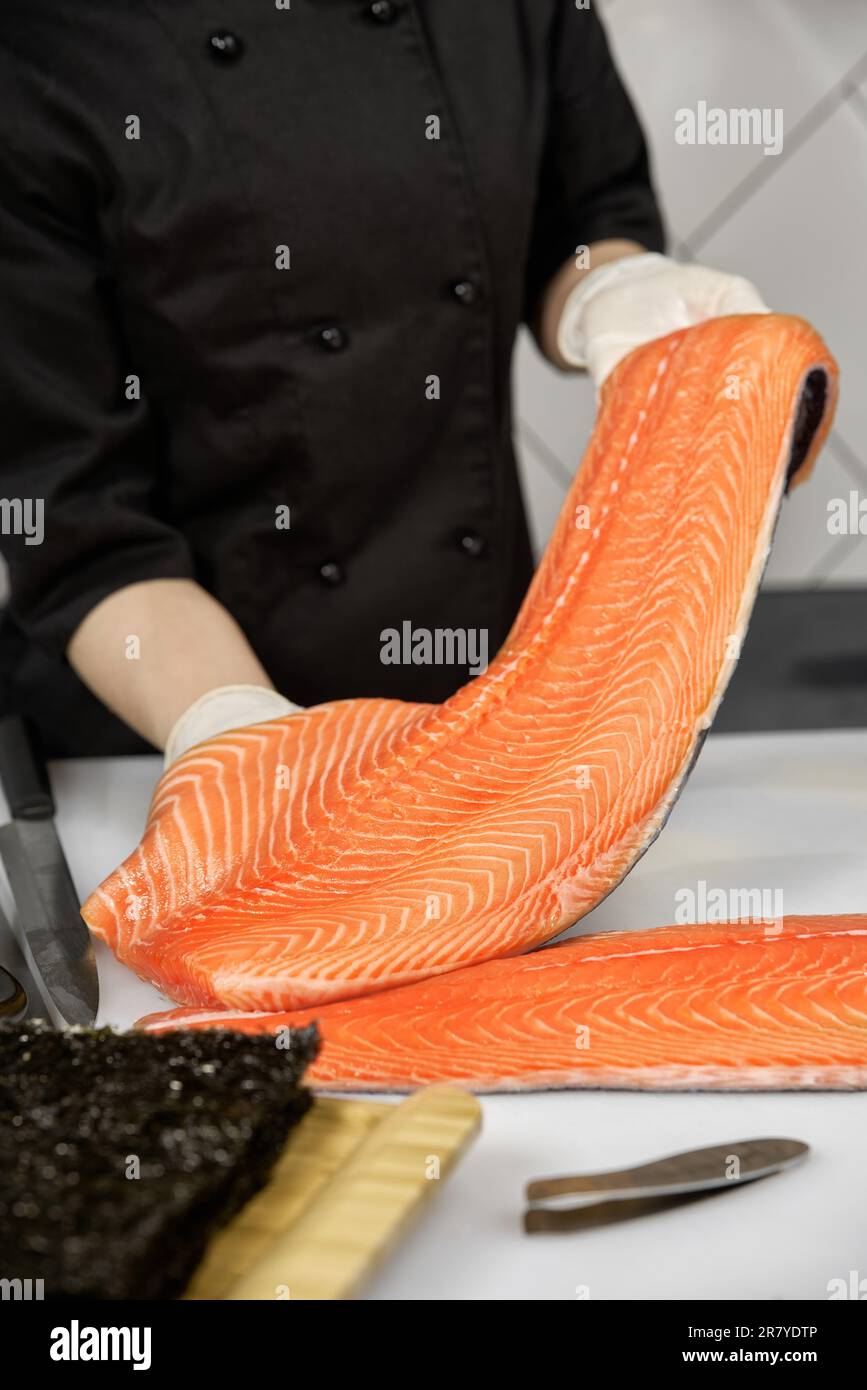 Portrait of cheerful chef standing with salmon fish. Chef cutting fish ...
