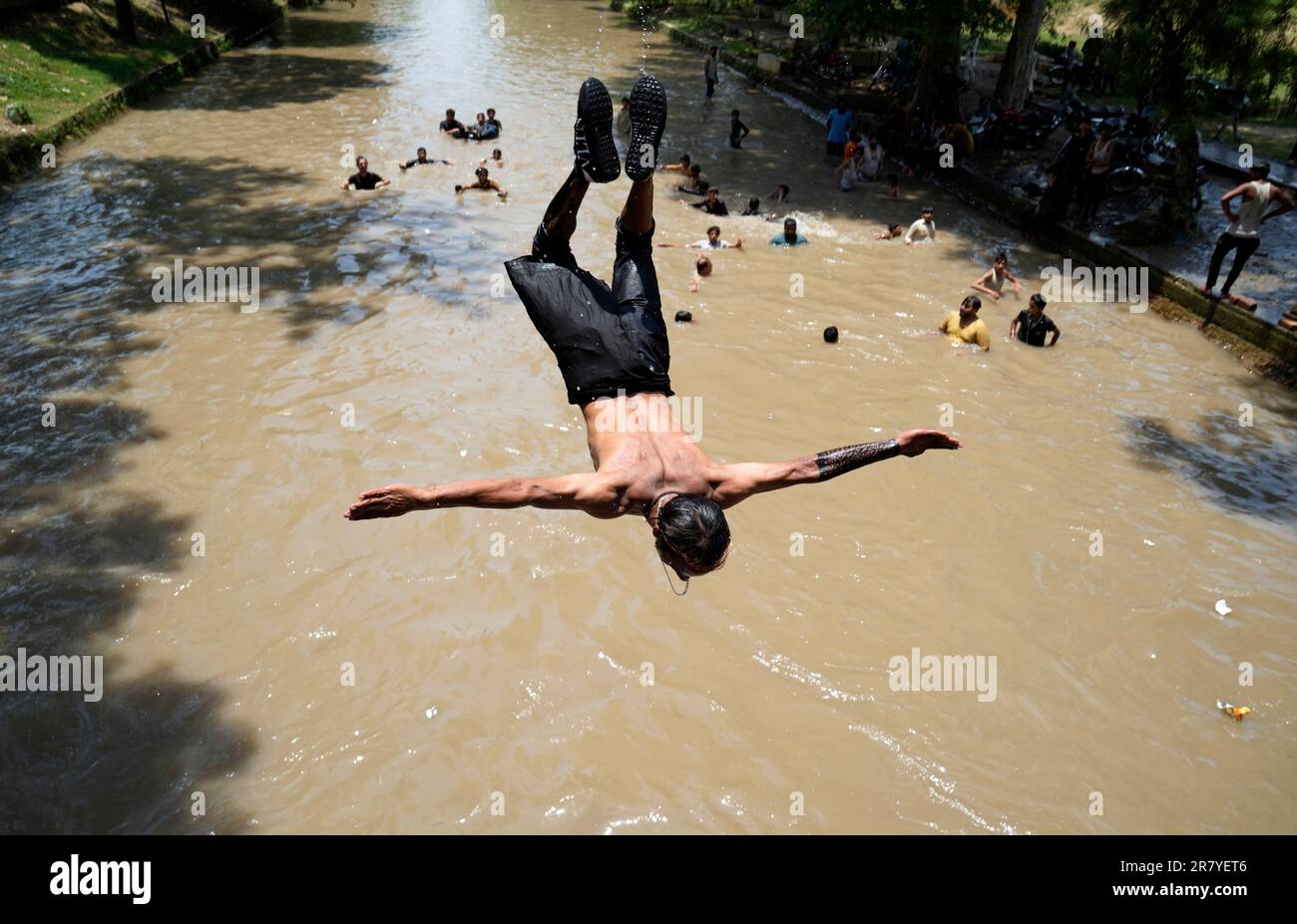 A Pakistani youth jumps into the water as he and others swim in a canal ...