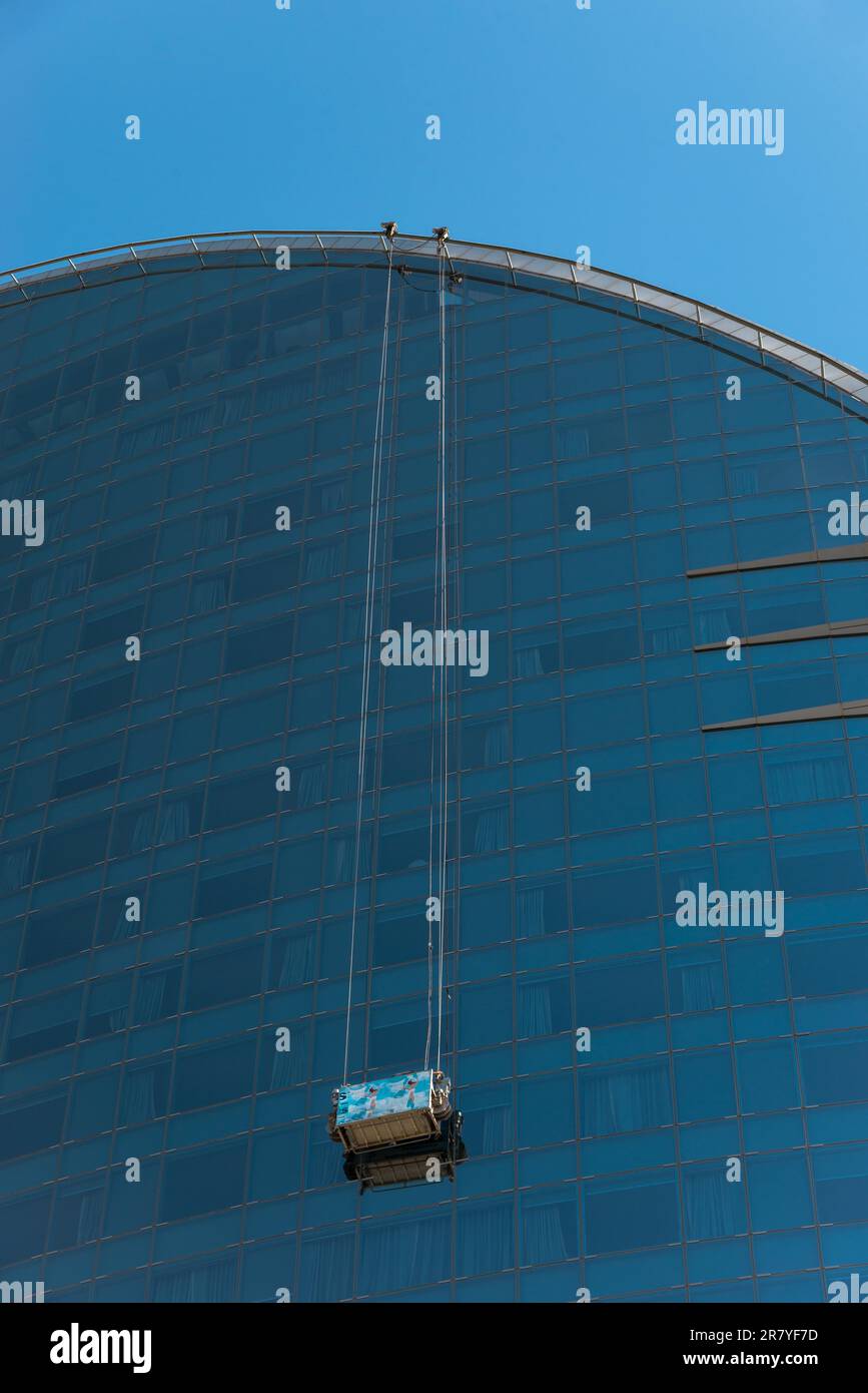 Worker or window cleaner on a swing stage at the W-Barcelona Hotel in Barceloneta. The building ...