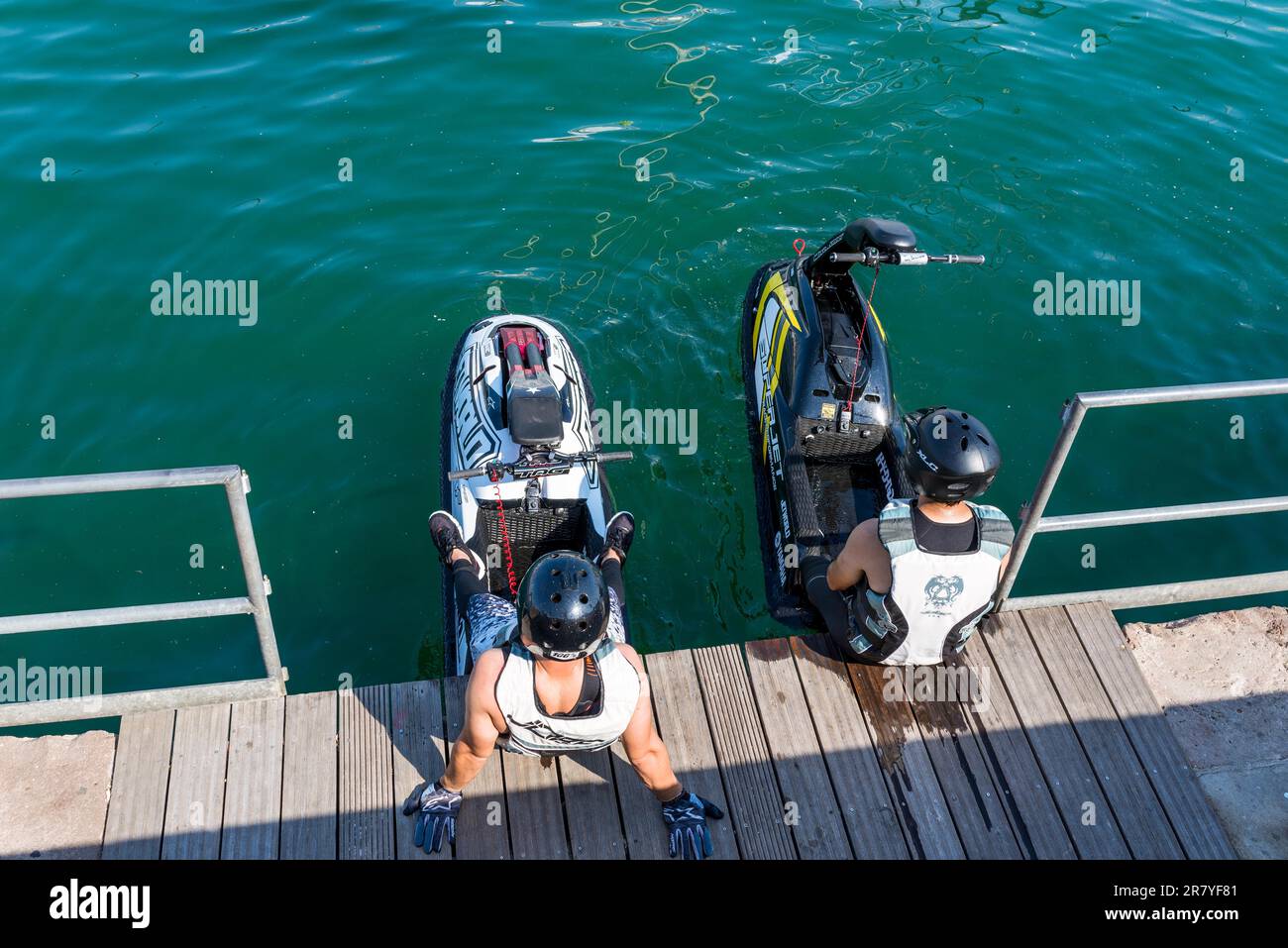 Two personal watercraft rider sit on the pier in the marina Port Vell ...