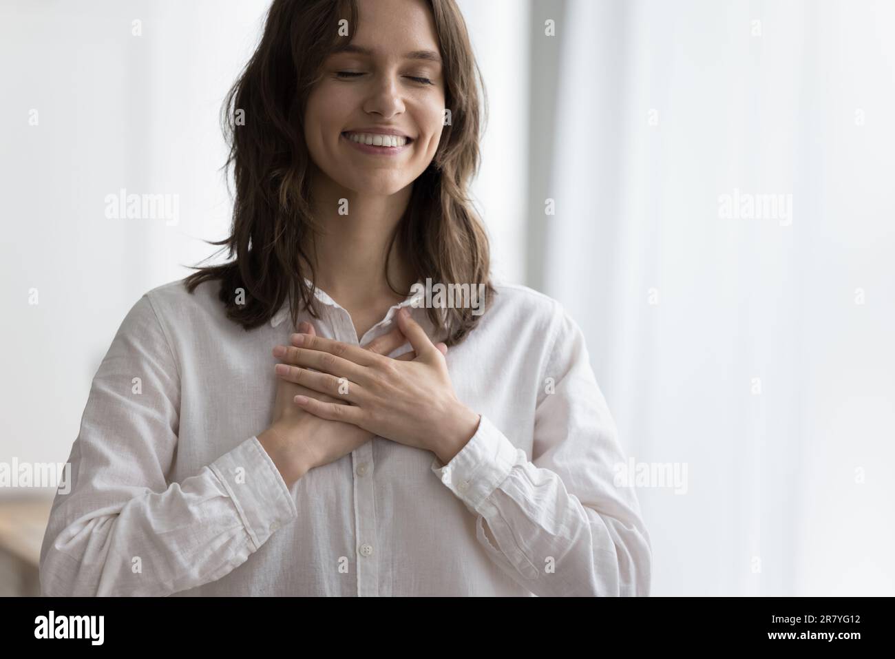 Lady holding folded hands on heart chest, feeling gratitude Stock Photo ...