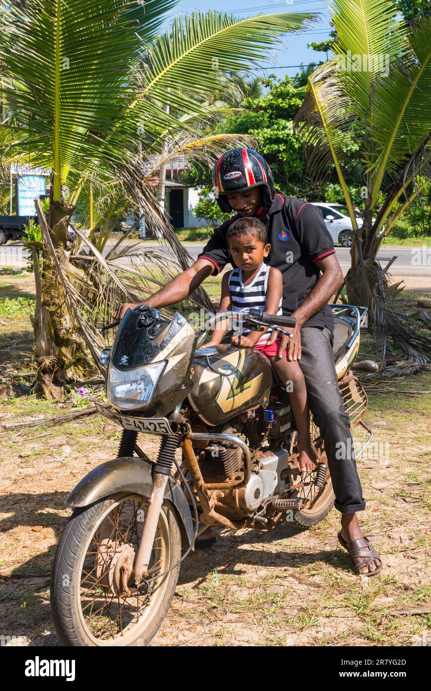 Proud father with his son on the Motorbike in Telwatta. Sceptical look ...