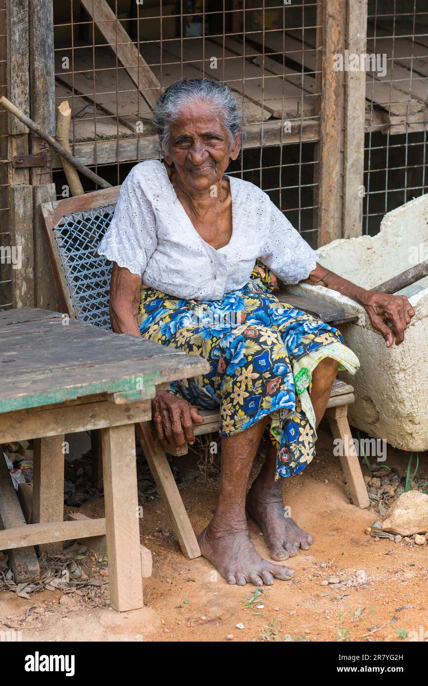 Old Grandma, poor but proud, sitting in front of their hut directly at ...