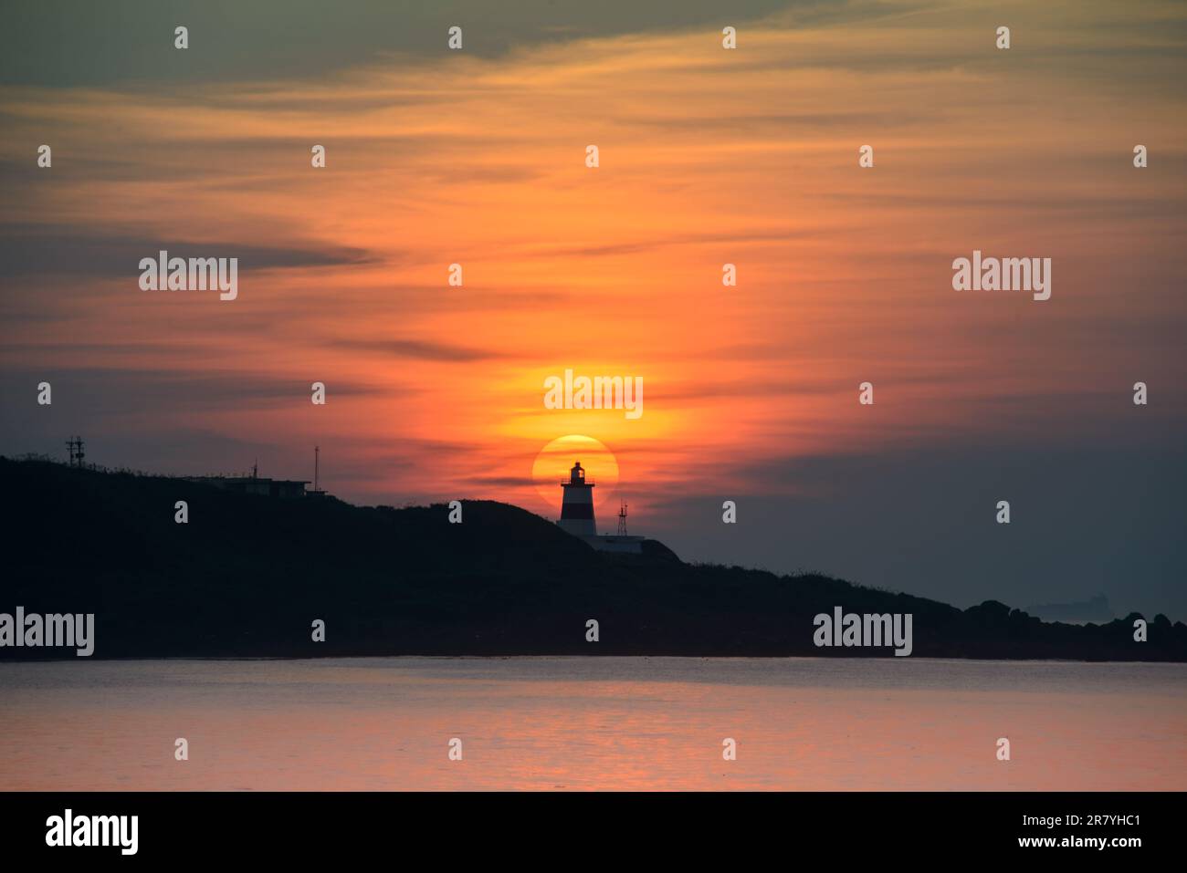 At dusk, the sun is behind the lighthouse. The Fugui Cape Lighthouse in ...