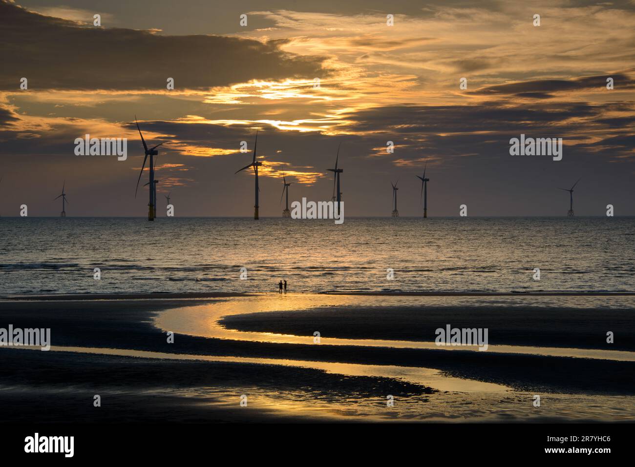 Fans of wind turbines spin over the sparkling sea. Dynamic clouds at ...