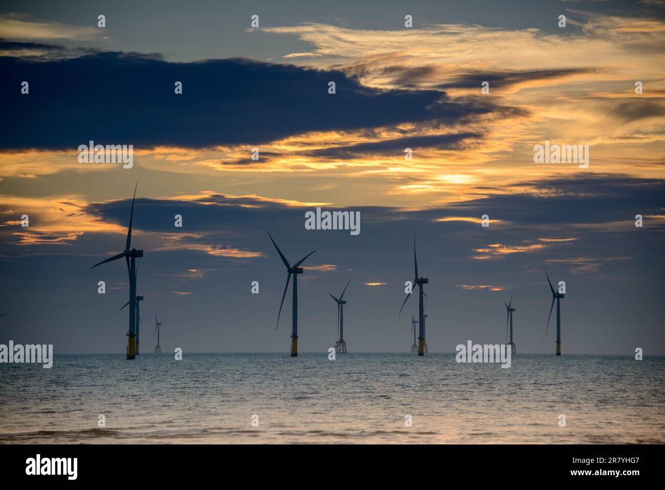 Fans of wind turbines spin over the sparkling sea. Dynamic clouds at ...