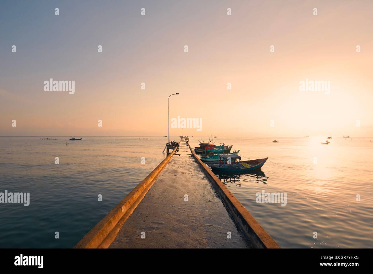 Sunrise over horizon of sea. Long pier with moored boats in fishing ...