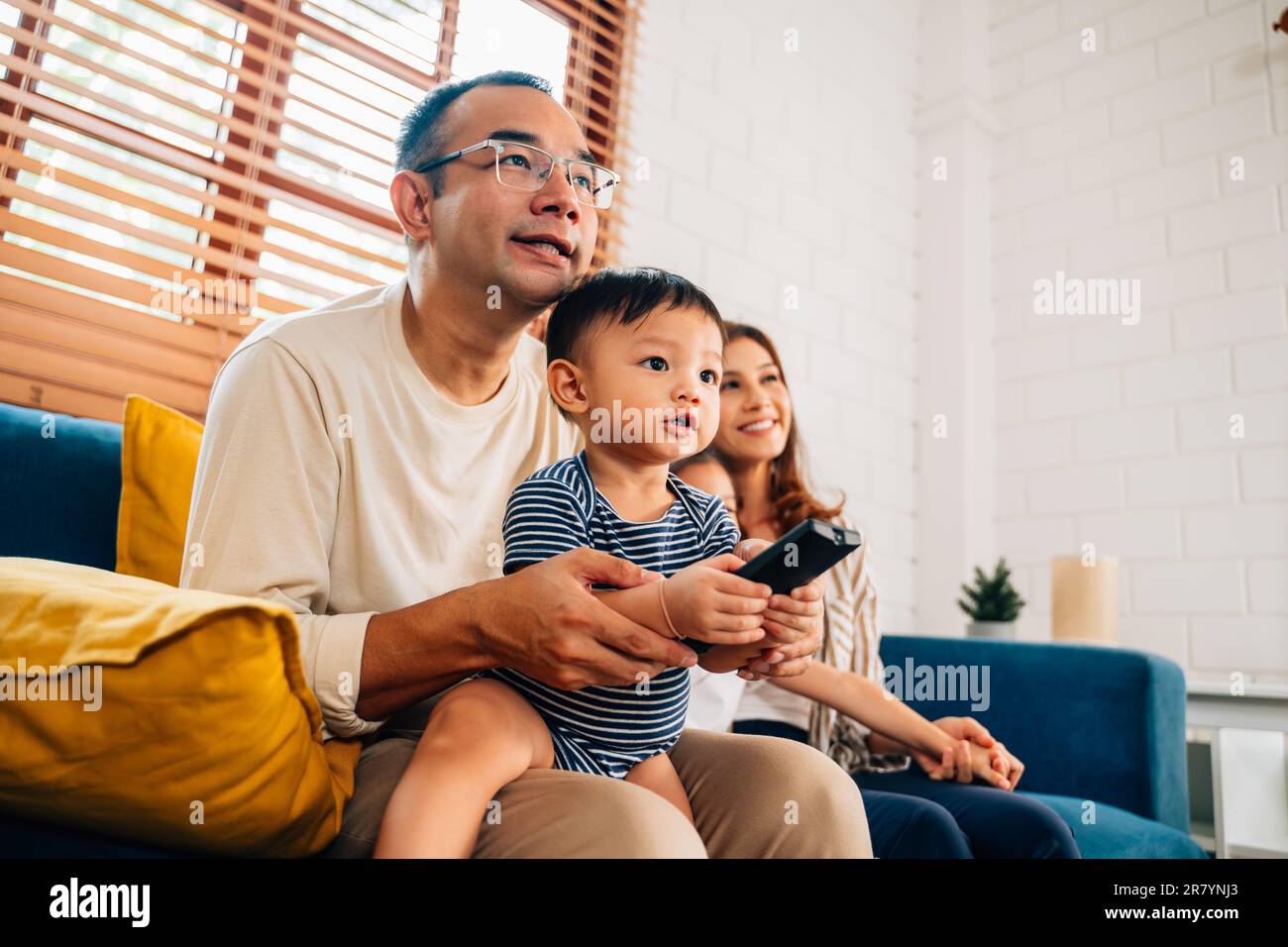 Happy family watching television together at living room Stock Photo ...