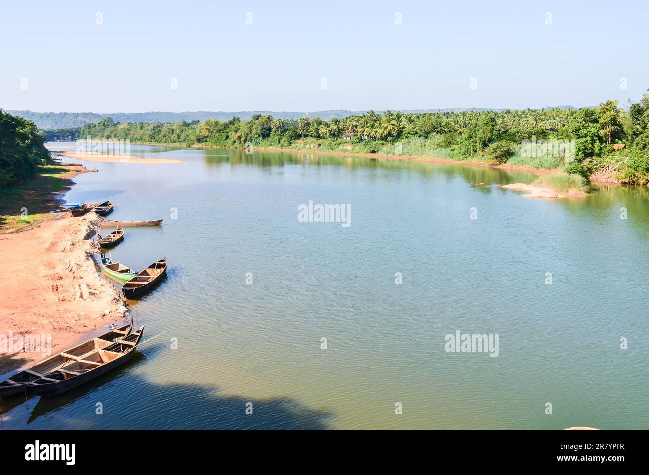 River with lush green river bank and sand mining boats at Polali ...