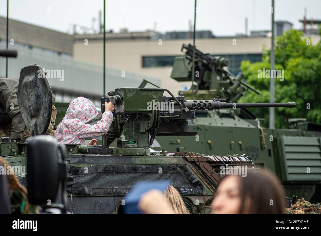 Kid or child playing with a machine gun on an armoured military vehicle ...