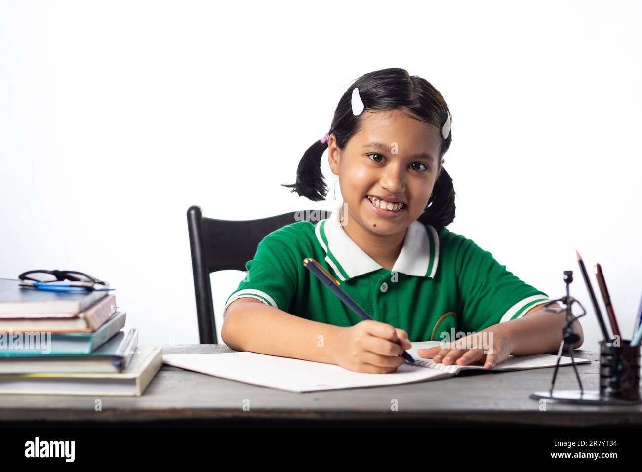 A pretty beautiful Indian schoolgirl child studying, writing on study ...