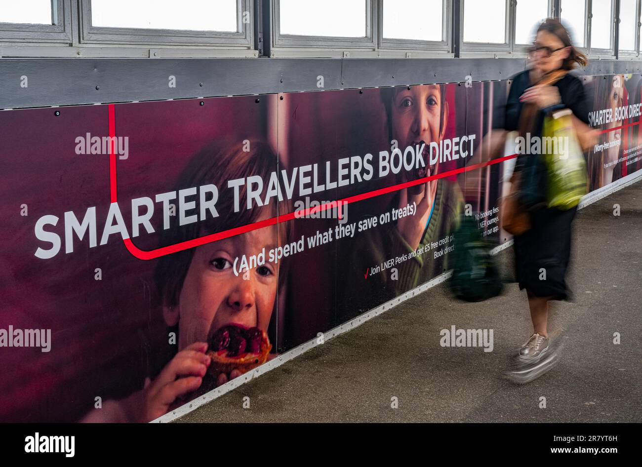 A young woman walking past an advertising hoarding for London North ...