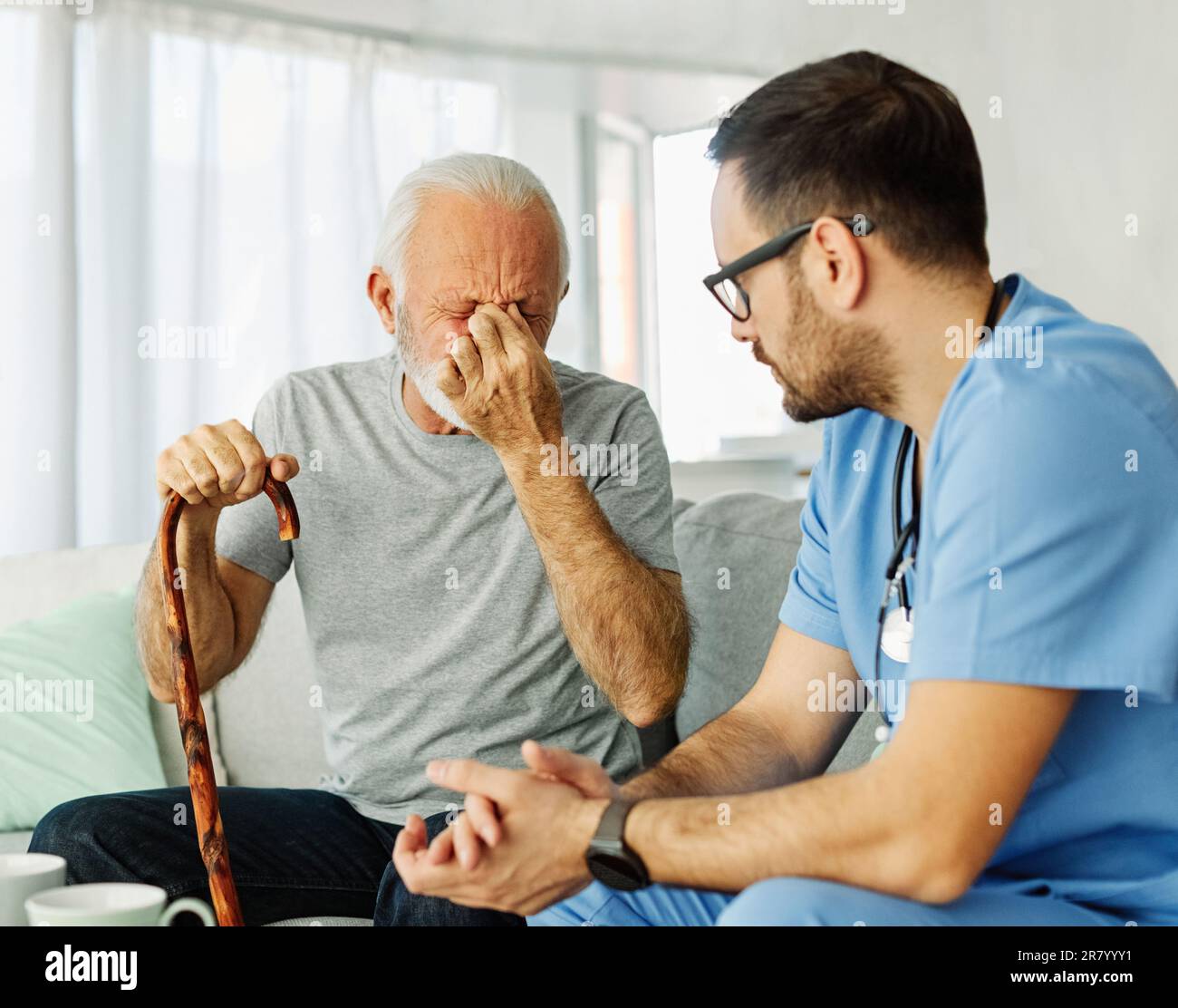 Doctor or nurse caregiver help senior man in pain at home or nursing ...