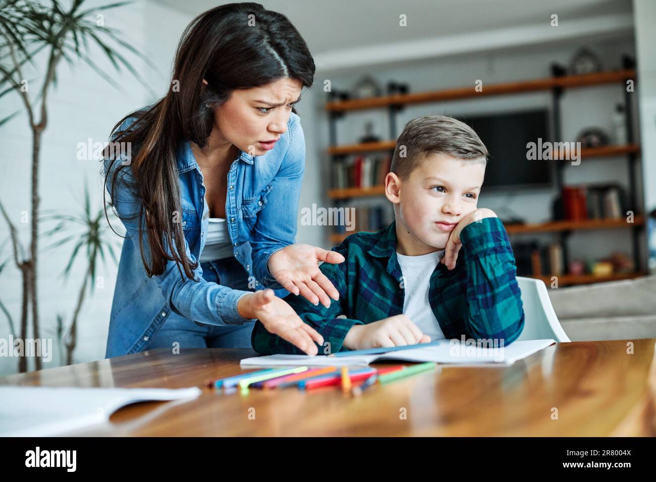 mother teaching bored son and helping with homework at home Stock Photo ...