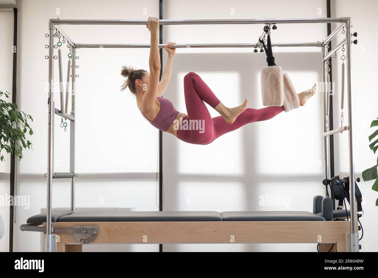 A caucasian woman is engaged in Pilates on a reformer simulator ...