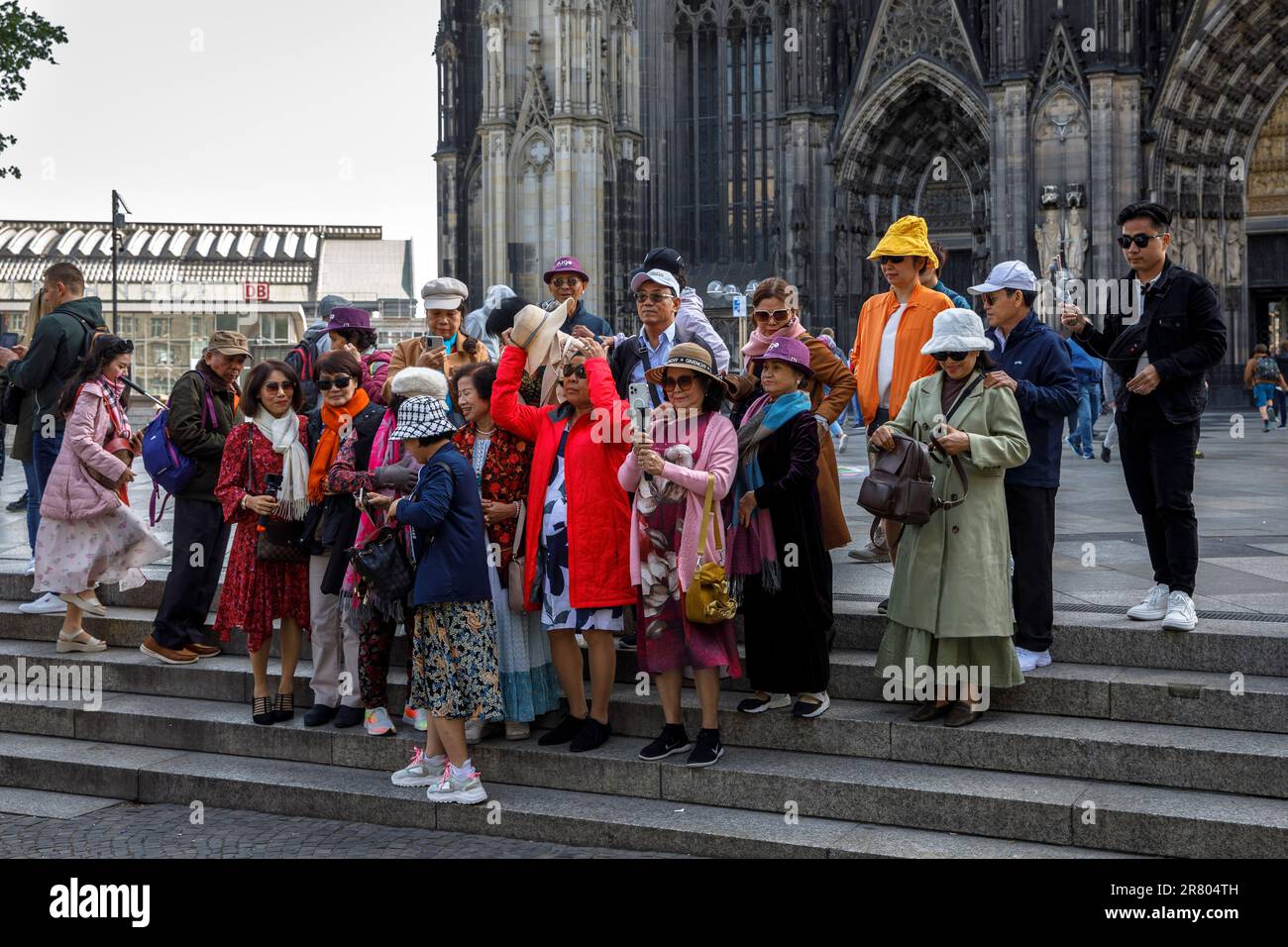 tourists from Asia pose for a group photo in front of Cologne Cathedral ...
