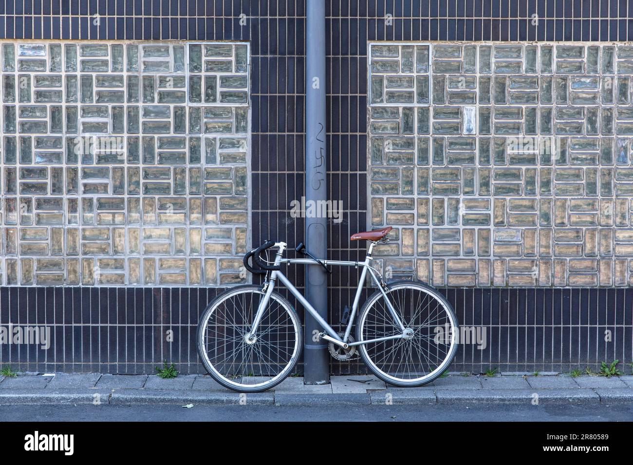 parked old silver racing bike in front of a wall with glass blocks in ...