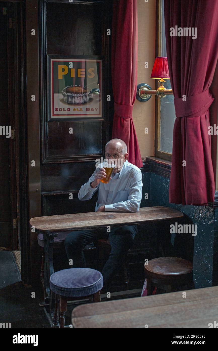 Male drinking a pint of beer inside the traditional pub Guinea Grill in ...