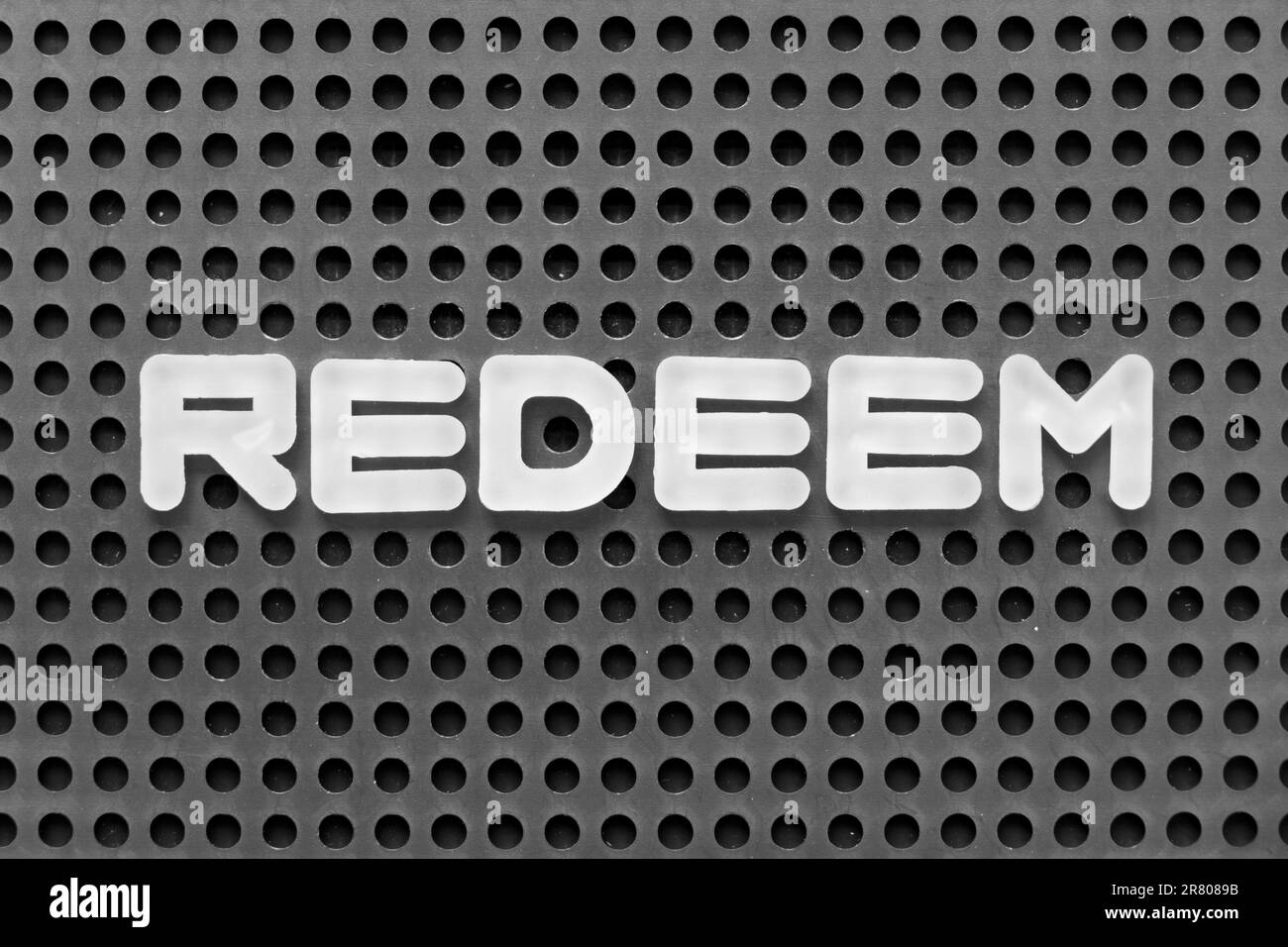 White alphabet letter in word redeem on black pegboard background Stock ...