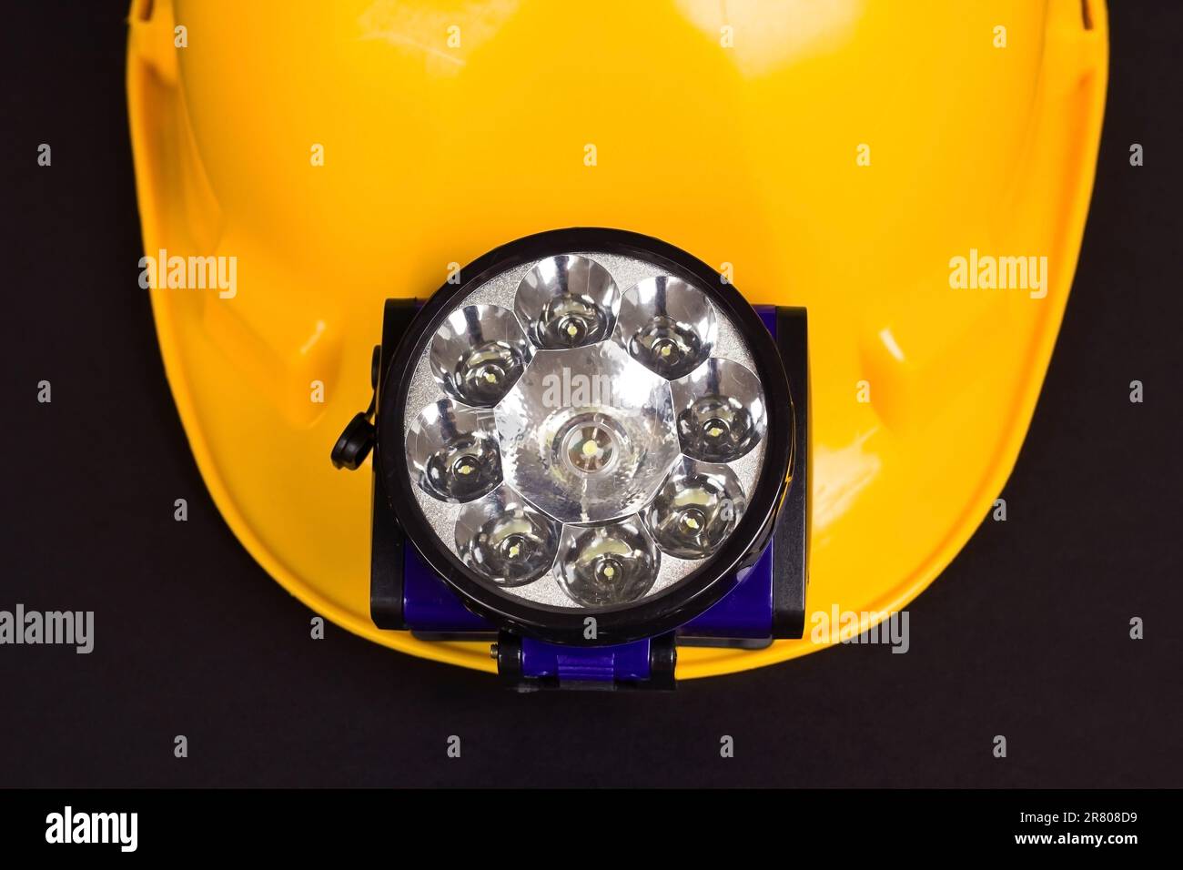 Yellow worker's hard hat,helmet on black background with overhead light ...