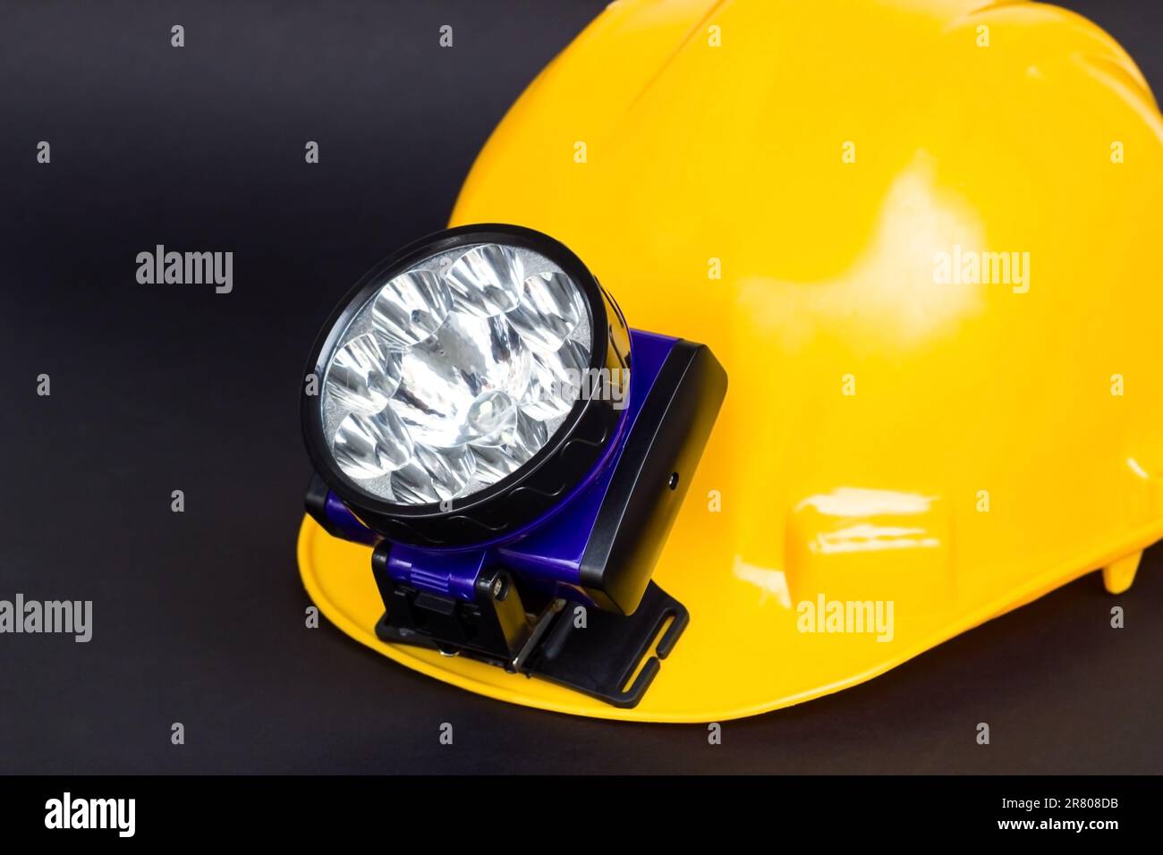 Yellow worker's hard hat,helmet on black background with overhead light ...