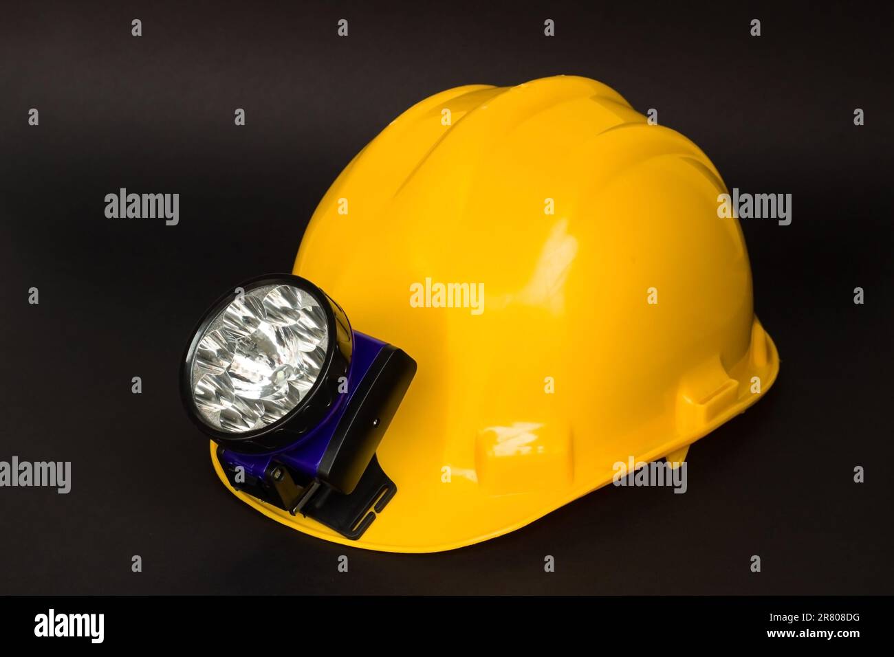 Yellow worker's hard hat,helmet on black background with overhead light ...