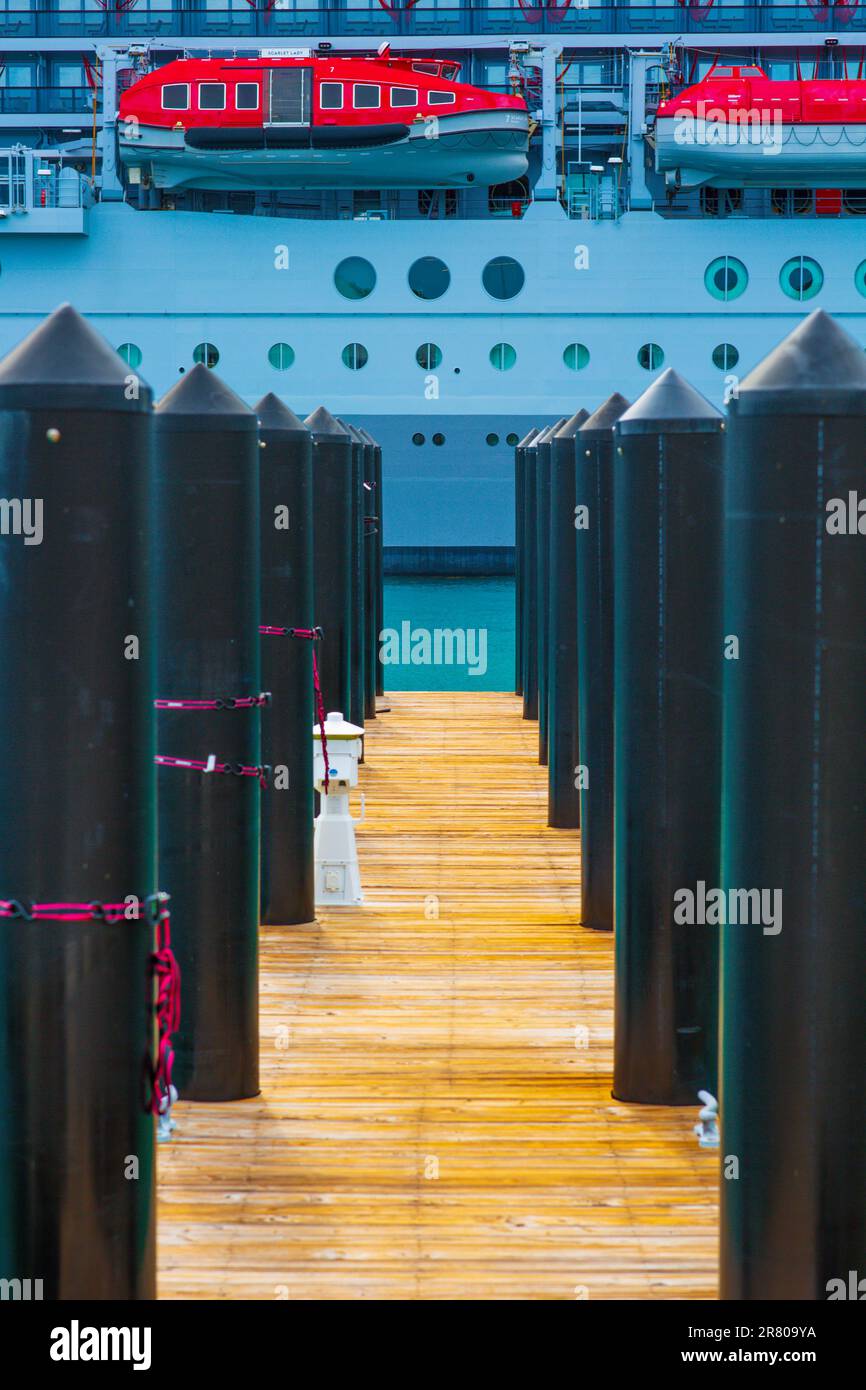 A cruise ship docked at a marina, with a series of vertical poles ...