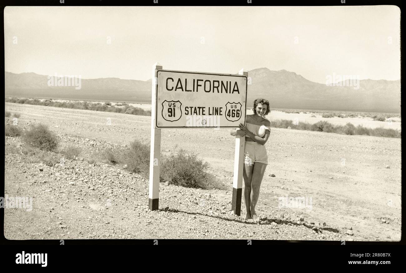 California State Sign 1950s. Woman standing by California sign along ...
