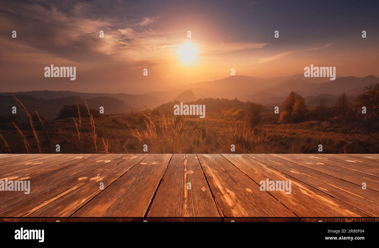 Colorful autumn sunset with sun rays coloring the hills. empty wooden ...
