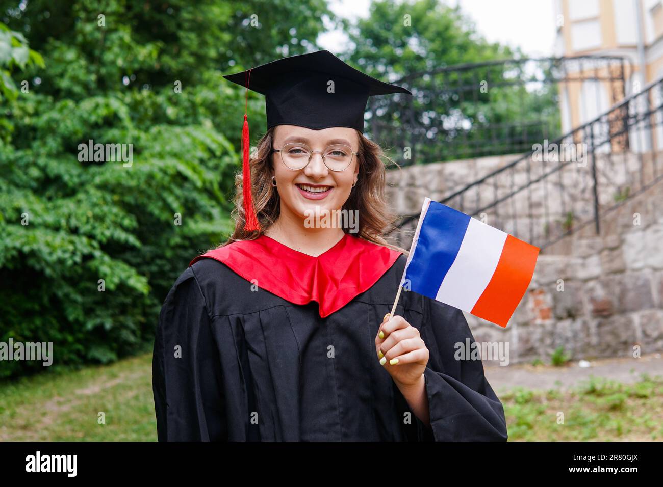 Young french woman wearing graduation gown and hat holding flag of ...