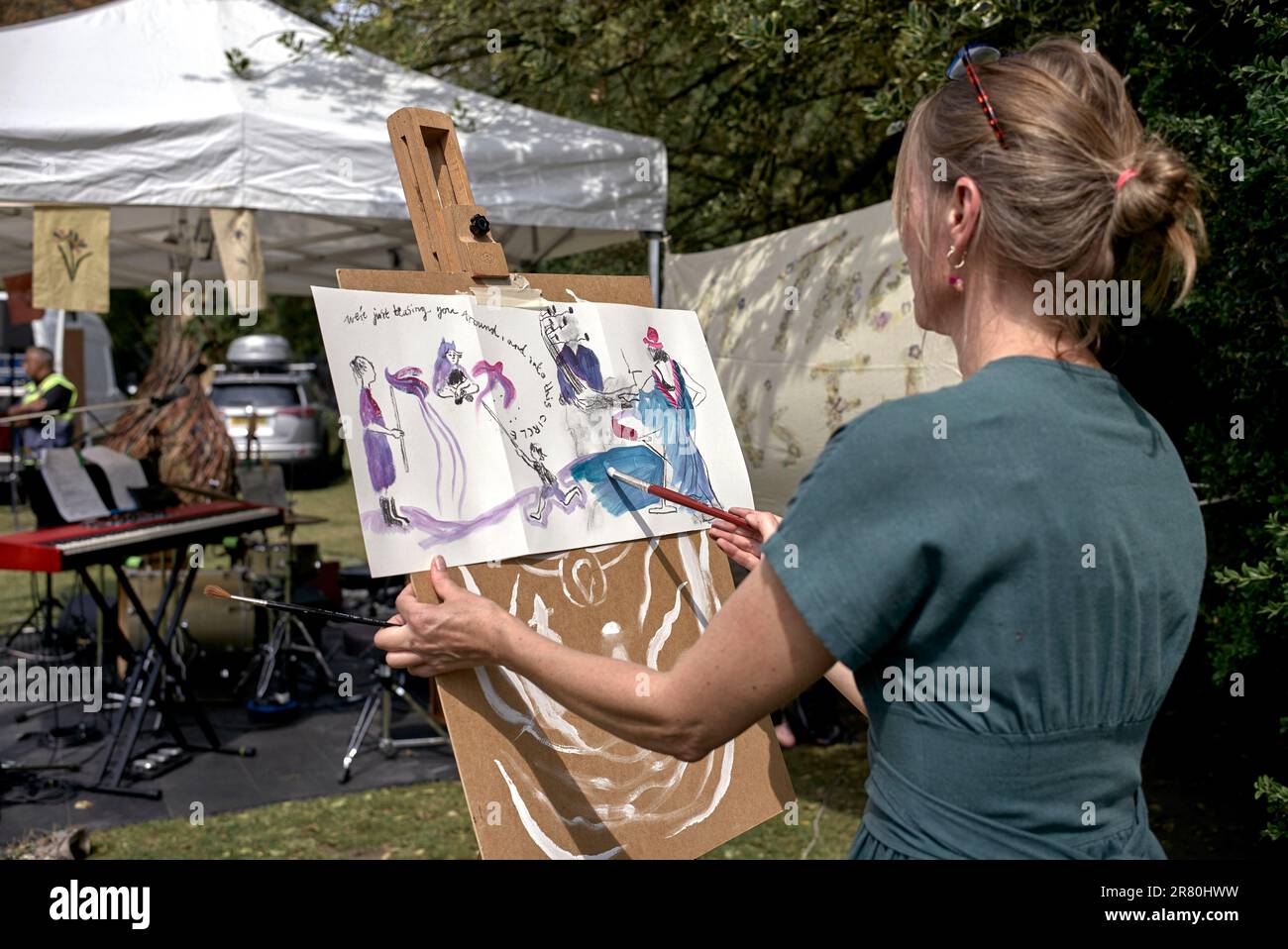 Woman artist painting a scene at a friends of the earth festival ...