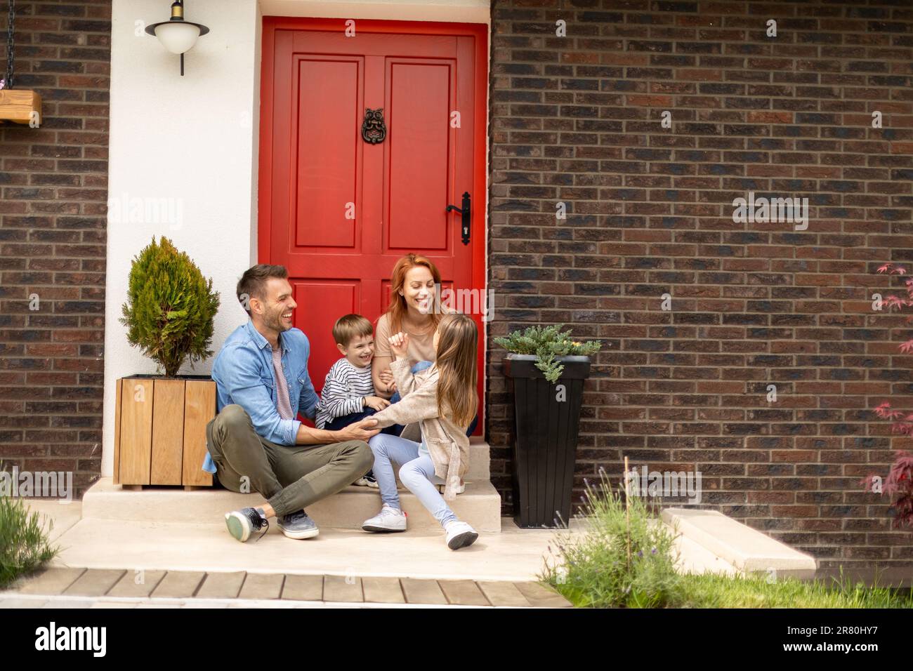 Family with a mother, father, son and daughter sitting outside on steps ...