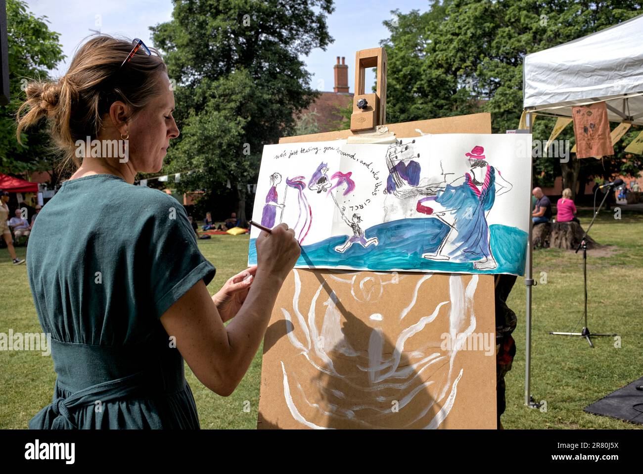 Woman artist painting a scene at a friends of the earth festival ...