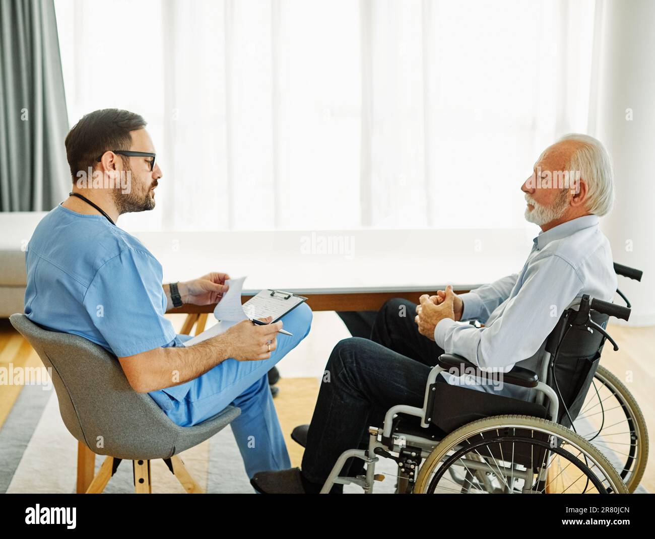 Doctor or nurse caregiver with senior man in a wheelchair holding a ...