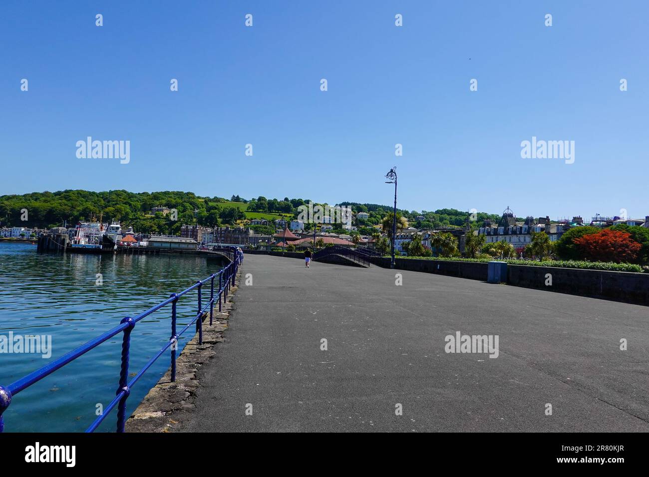 People on the esplanade with green rolling hills and clear blue skies ...