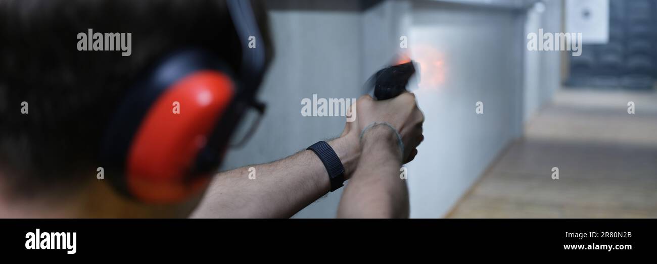 Shooter man holding gun in hand and shooting at a target rear view ...