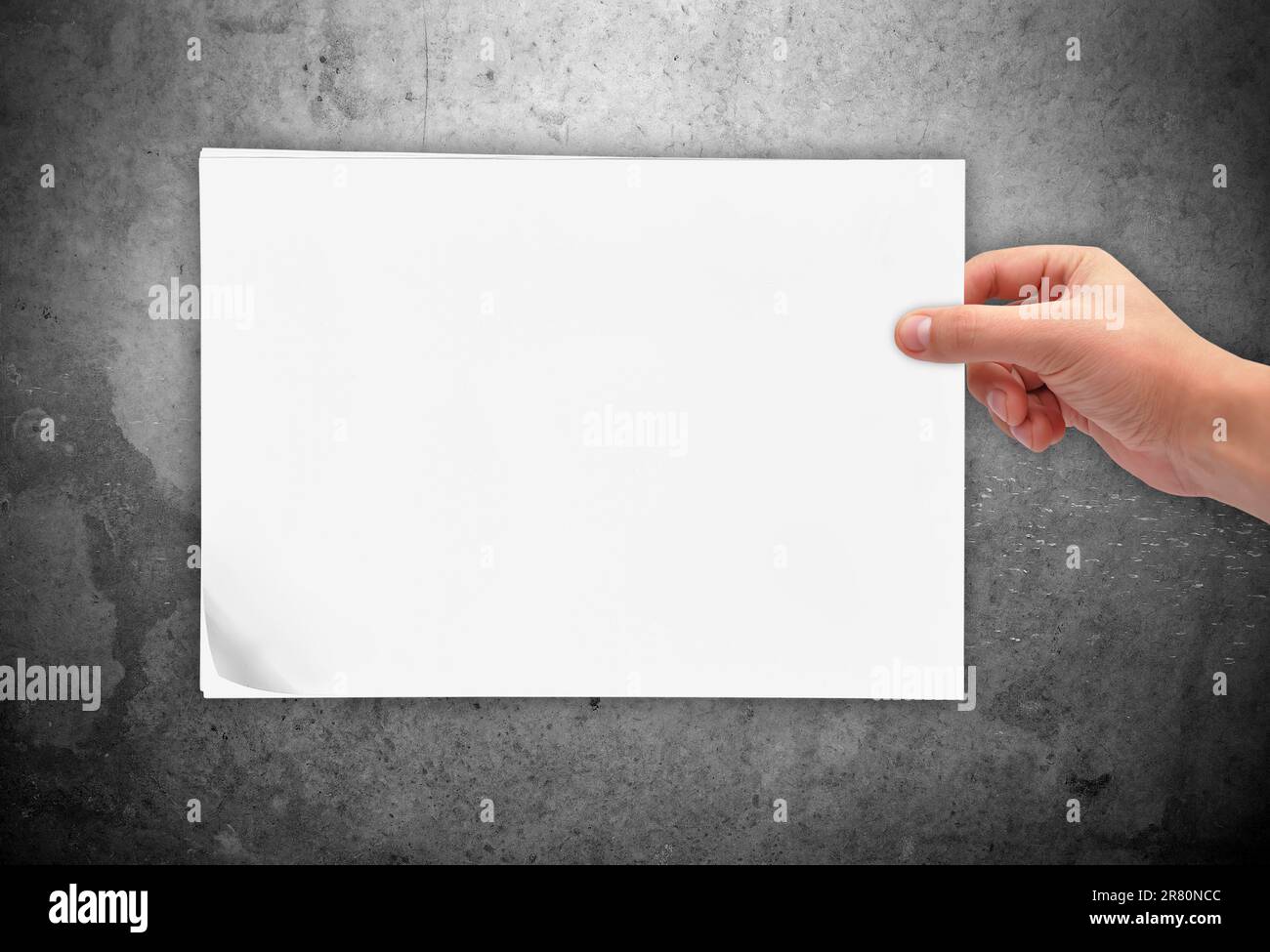 hand holding blank paper on a concrete wall background Stock Photo - Alamy