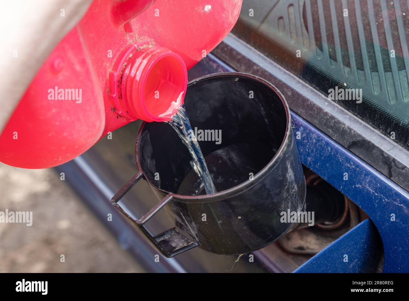 Pouring fuel with funnel in a car gas tank from red can Stock Photo - Alamy