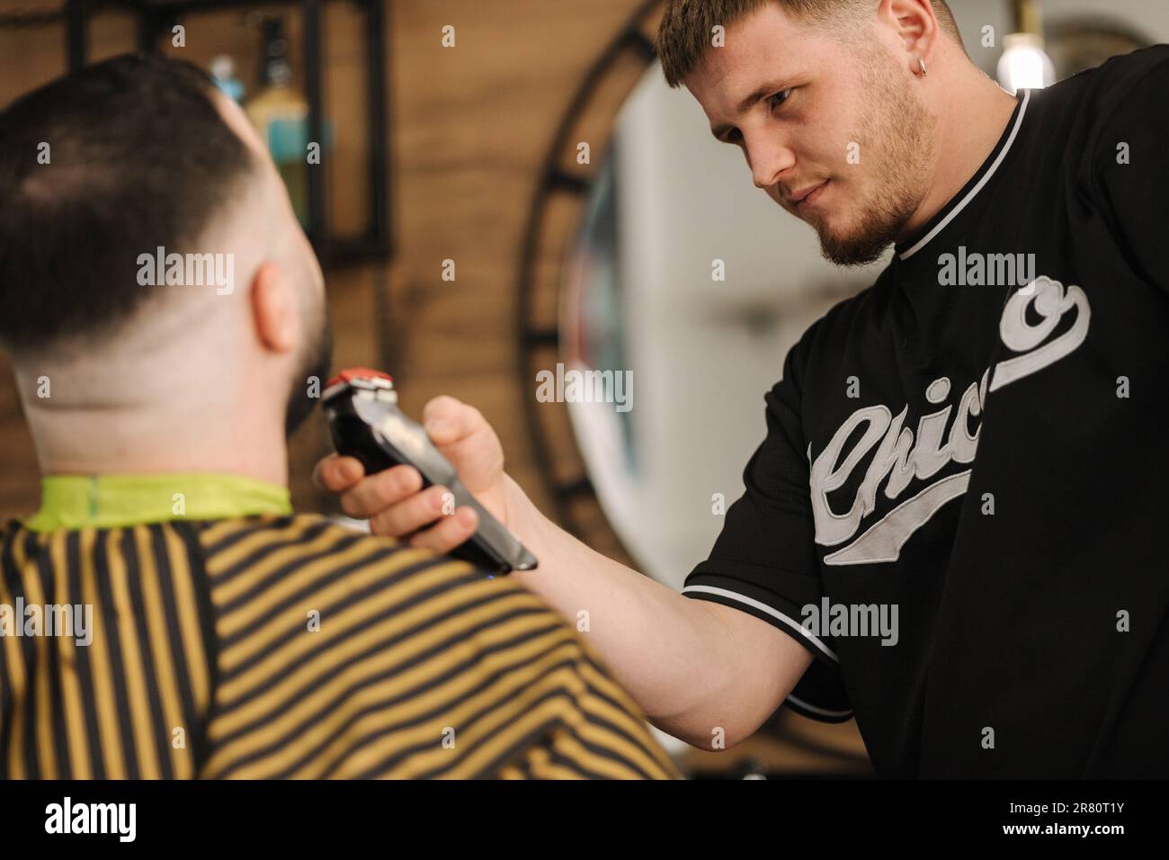 Professional barber shaves man's hairs in barber shop. Back view of ...