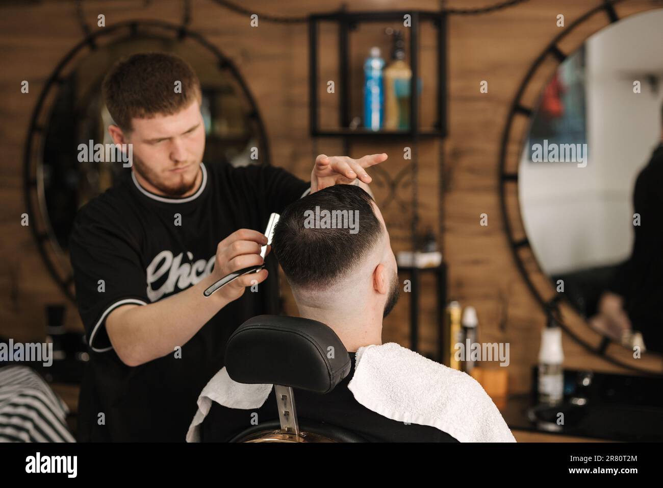 Back view of barber using sharp blade for shaving. Handsome customer ...