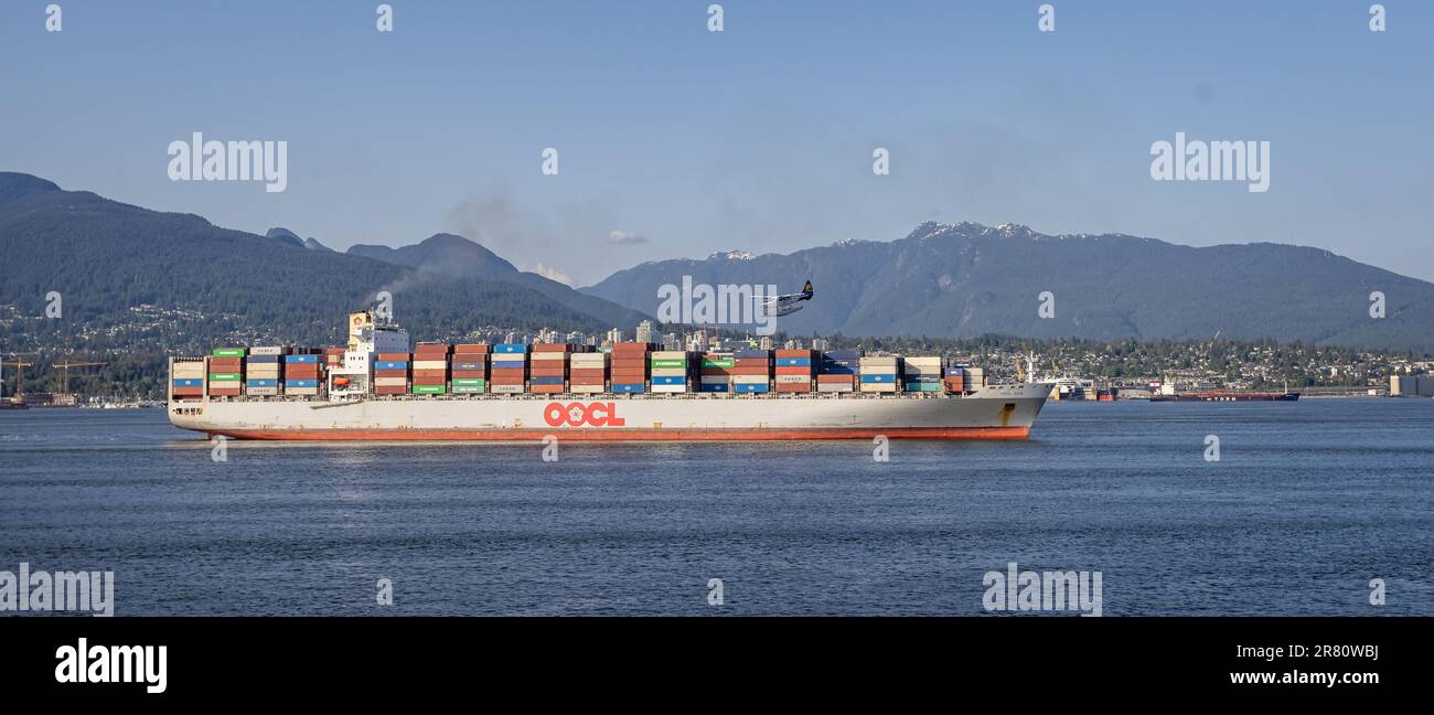 Large container ship with seaplane flying overhead heading for port in ...