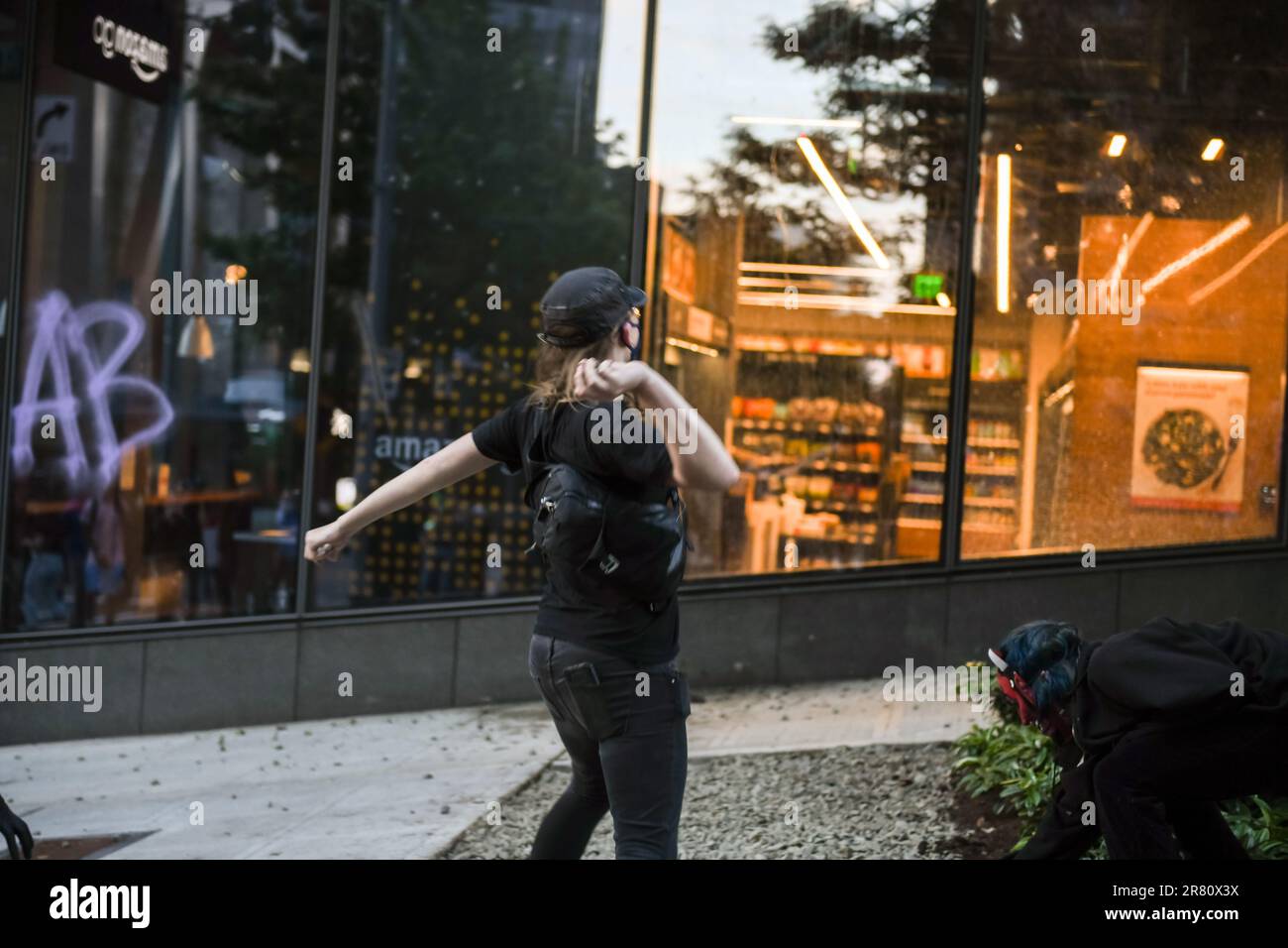 Seattle, USA. 29 May, 2020. A protestor throwing a rock at the Amazon ...