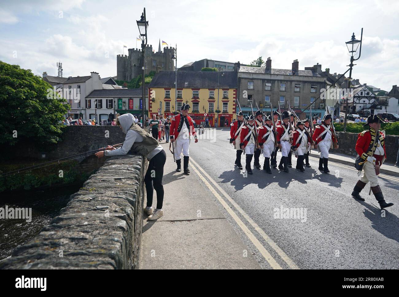 A man fishes on the bridge as behind him re-enactors recreate the ...