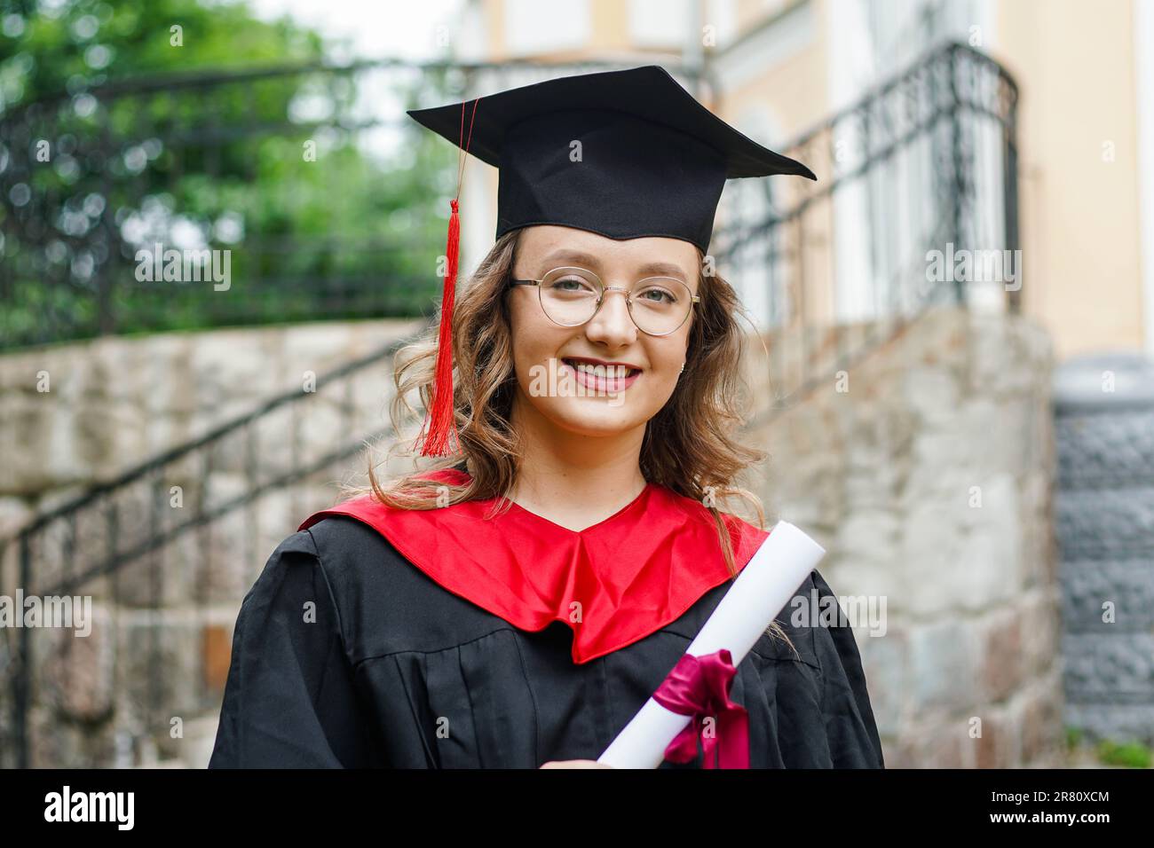 Portrait of a beautiful smiling graduated student girl in black ...
