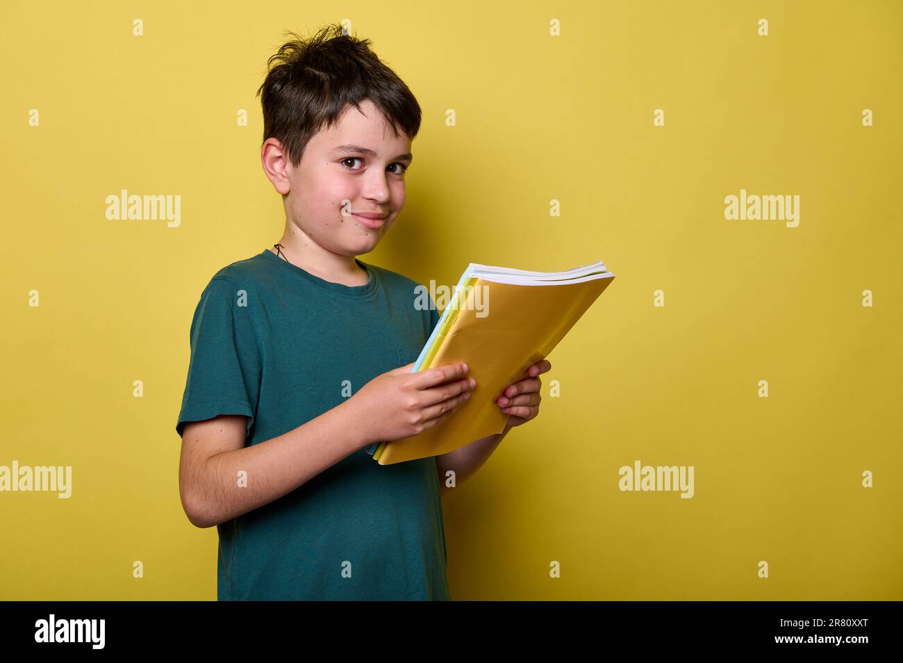 Handsome teenage boy smiling looking at camera, holding textbooks ...