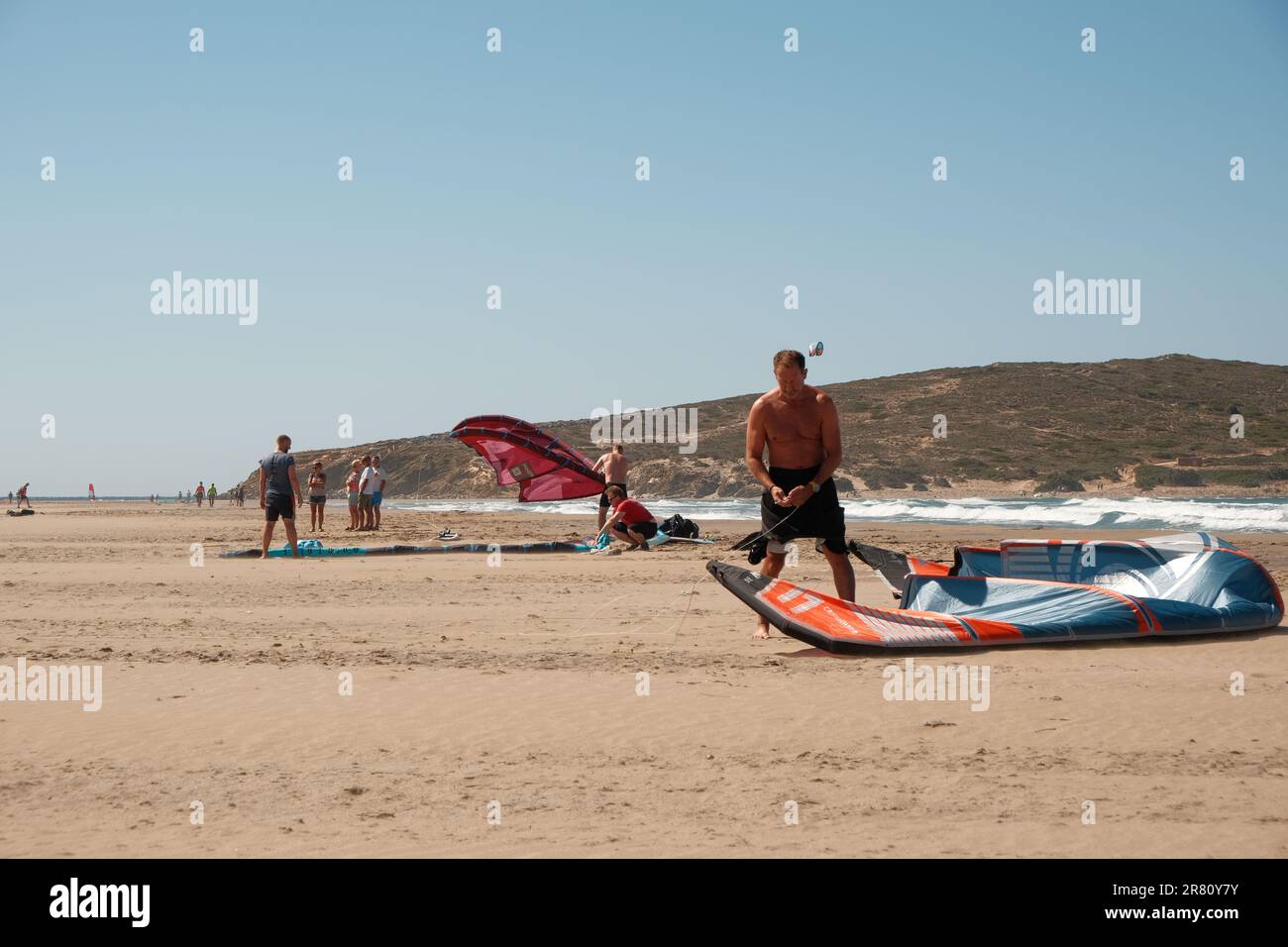 surfer preparing his kite sail which is lying in the sand of prassonisi ...