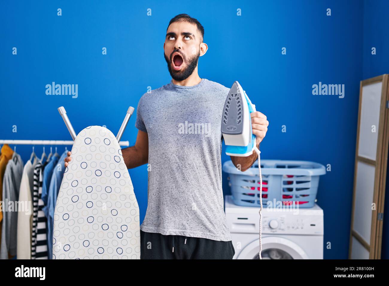Middle east man with beard holding electric iron angry and mad ...