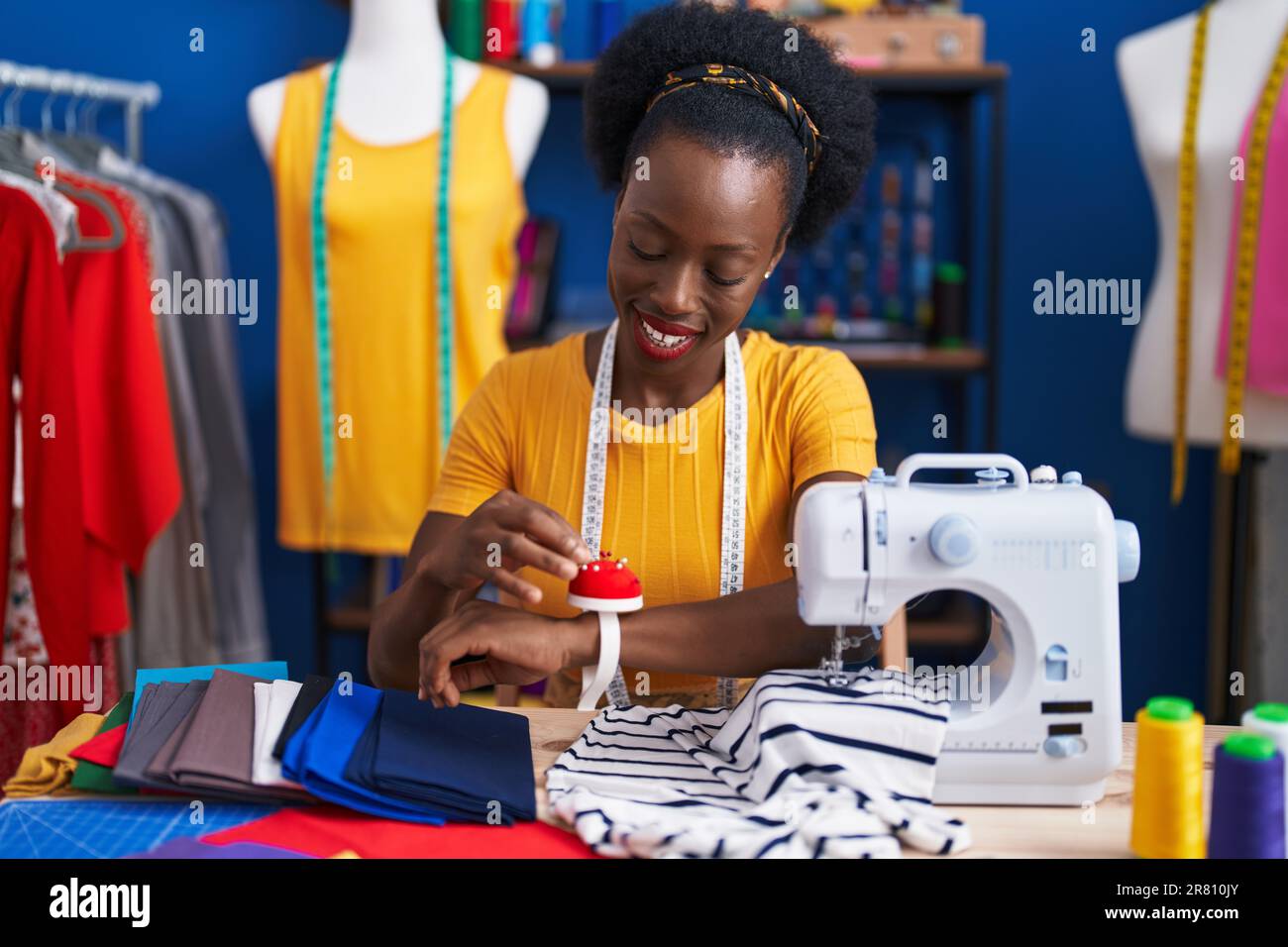 African american woman tailor using sewing machine holding pin at ...